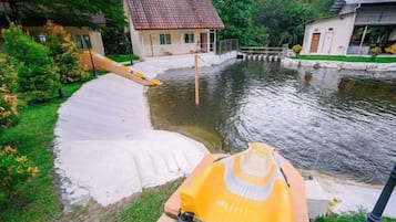 Área residencial com piscina, uma estrutura inflável amarela e uma pequena ponte sobre a água.