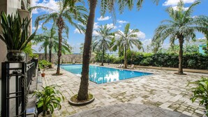Uma área de piscina com palmeiras e piso de azulejos.