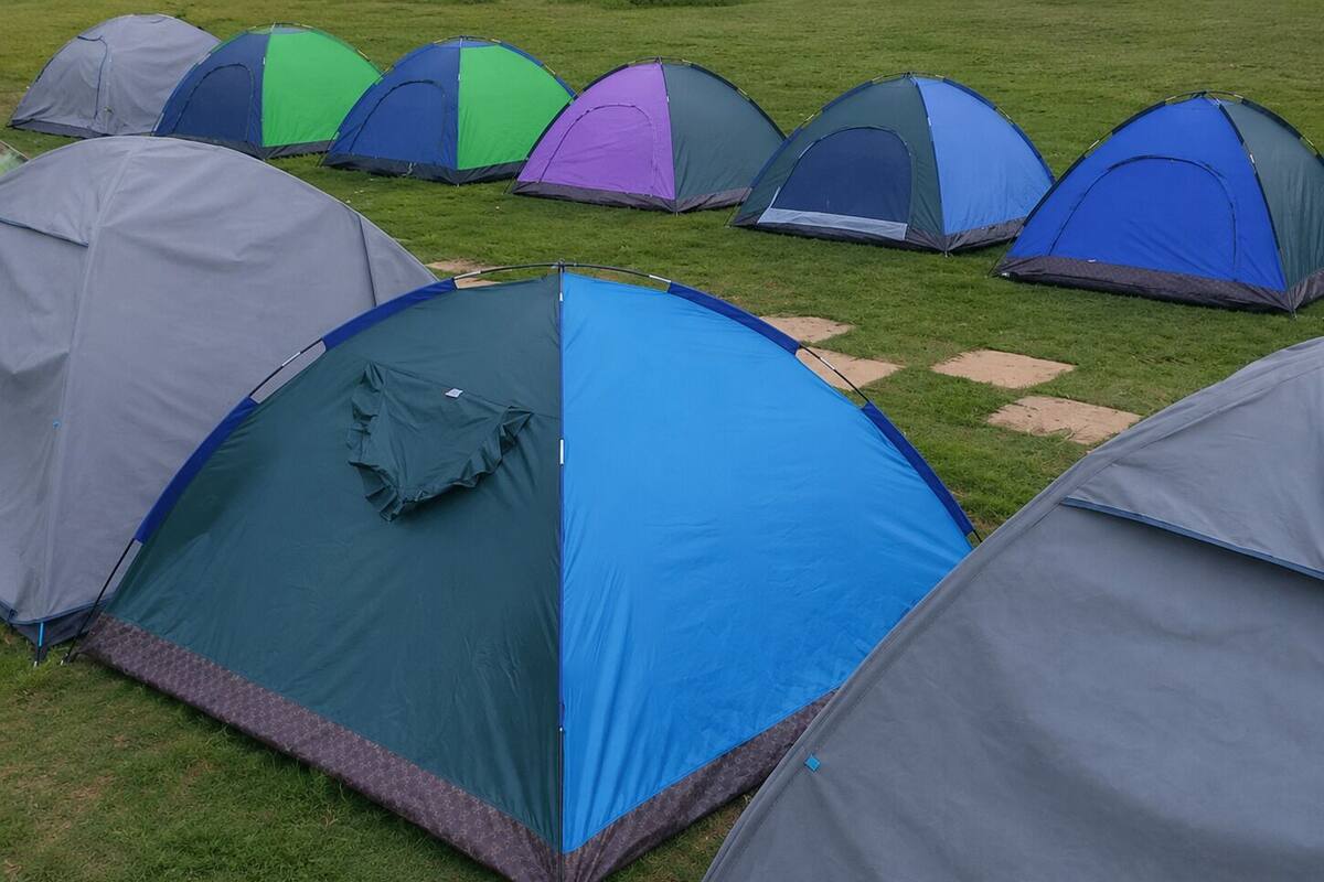 Várias tendas dispostas em fileiras num campo relvado.