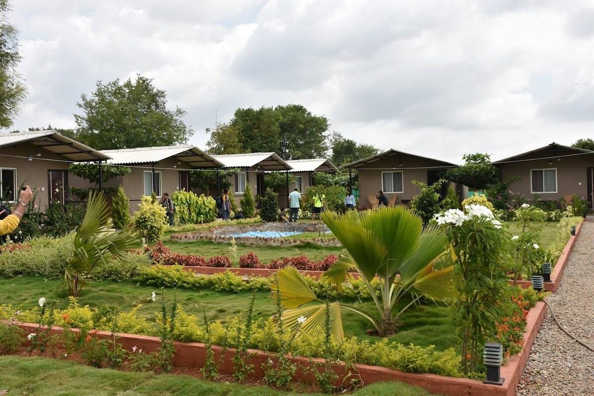 Uma fileira de cabanas térreas com um jardim bem cuidado na frente.