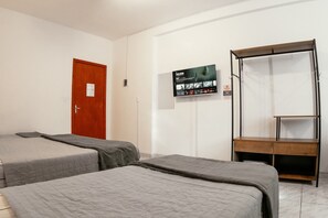Quarto com duas camas, guarda-roupa de madeira, televisão fixada na parede e porta com um aviso.