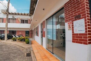 Um edifício com fachada de tijolos vermelhos, entrada de vidro e uma placa indicando que não é permitido estacionar.