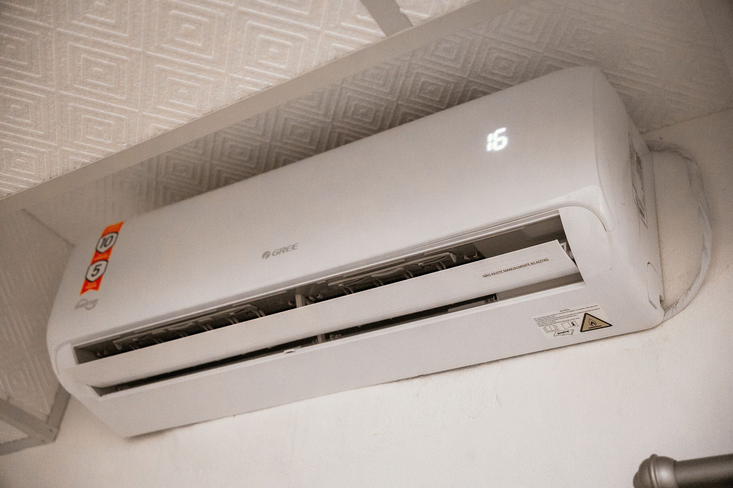 Unidade de ar condicionado branca fixada na parede com padrão geométrico.