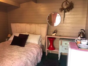 Quarto com cama, mesa de cabeceira, cômoda, espelho e uma grinalda na parede.