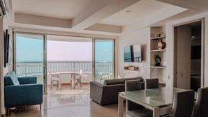 Uma sala de estar moderna com varanda, área de jantar e televisão na parede.