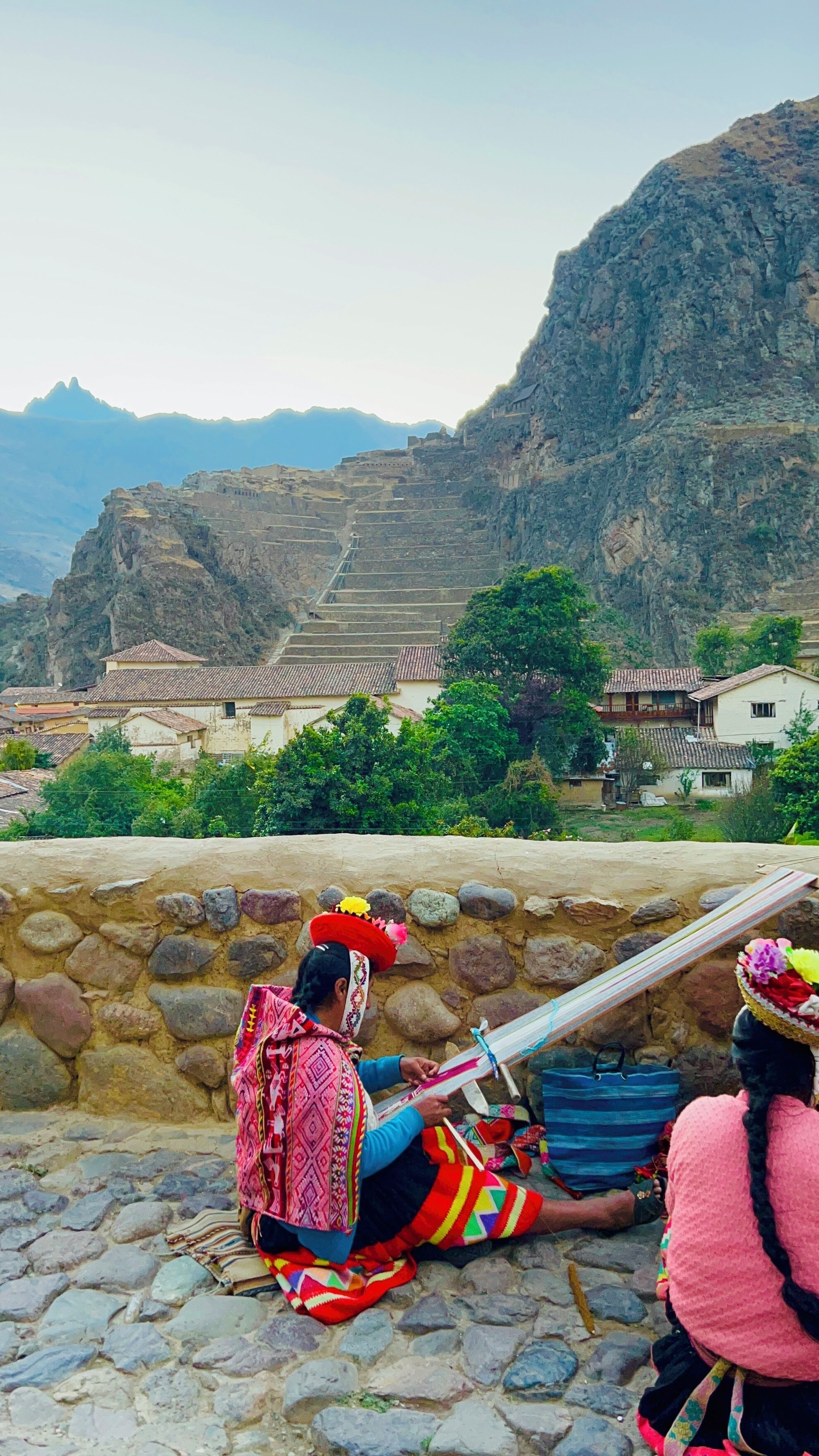 Uma aldeia andina tradicional com edifícios de pedra e campos em socalcos.