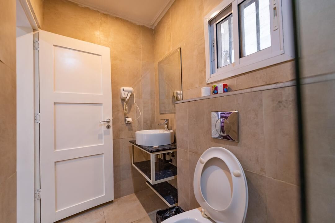Casa de banho compacta com sanita branca, lavatório e espelho em cima.