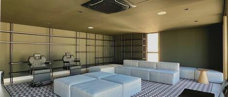 Uma sala de estar moderna com um sofá modular, um tapete estampado e um respiradouro no teto.