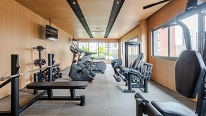 Uma academia com equipamentos de ginástica, janelas amplas e teto de madeira.