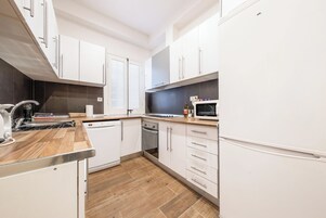 Cozinha moderna com armários brancos, bancada de madeira, forno embutido e micro-ondas.
