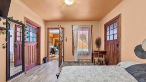 Quarto com uma cama grande, portas de madeira e vista para uma sala de jantar.