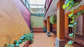 Um pátio coberto com telhas de barro, plantas em vasos e um pilar de tijolo.