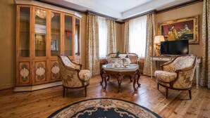 Uma sala de estar tradicional com um armário de madeira, duas poltronas, uma mesa de centro, uma televisão e um tapete estampado.