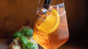 Um copo de cocktail com uma fatia de limão e duas canudos, sobre uma superfície de madeira.