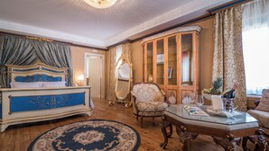 Um quarto luxuoso com uma cama grande, móveis elaborados, uma mesa de vidro e um armário de madeira.