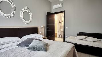 Quarto de hotel com duas camas, um espelho grande e porta de acesso a um banheiro.