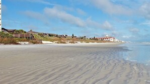Uma praia com um edifício ao fundo.