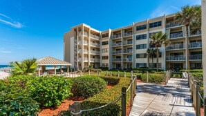 Um hotel de vários andares com varandas, área de estar coberta ao ar livre e um calçadão de madeira.