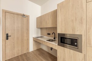 Cozinha moderna com armários de madeira, micro-ondas embutido e uma pia.