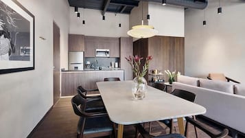 Cozinha moderna com ilha central, iluminação pendente e área de refeições com mesa e cadeiras.