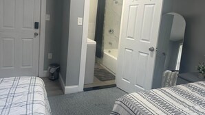 Quarto com duas camas, chuveiro e porta com a inscrição 'Toalhas'.