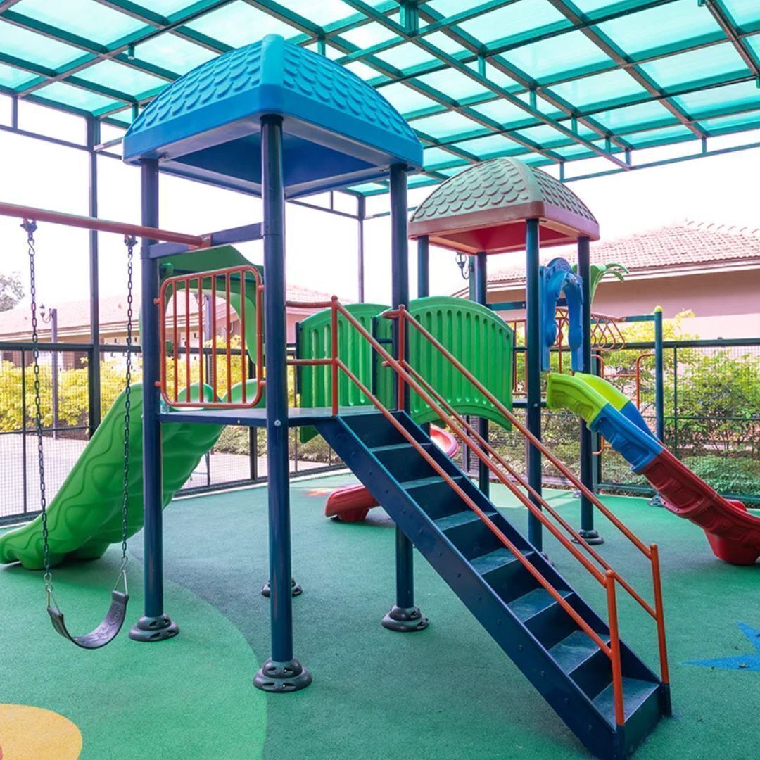 Espaço infantil com escorrega, estruturas de escalada e área de estar coberta.