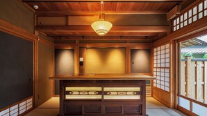 Um quarto japonês tradicional com tatames, uma mesa de madeira baixa, portas deslizantes e um lustre.