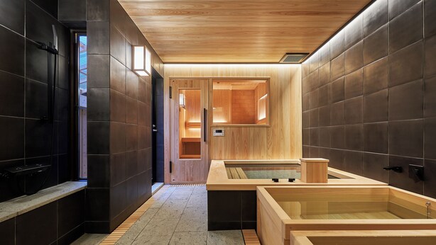 Um spa moderno com teto de madeira, uma banheira grande e uma pequena estante de madeira.