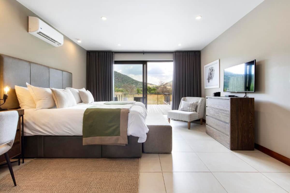 Quarto de hotel moderno com uma cama grande, televisão de tela plana, escrivaninha e vista para o exterior.