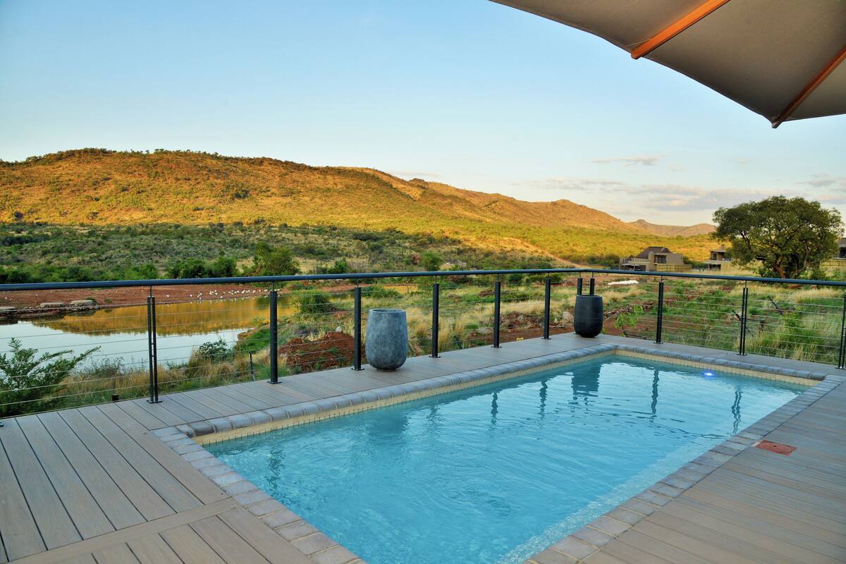 Piscina com vista para um lago e colinas.