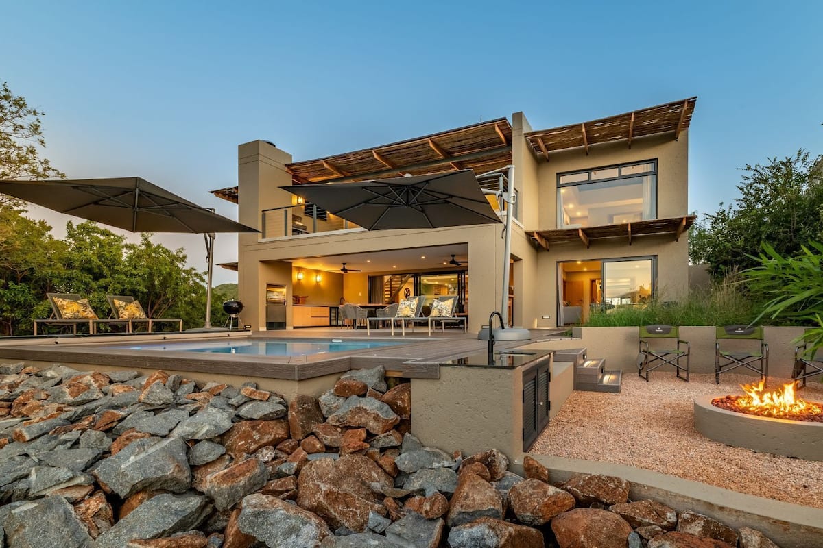 Uma casa moderna de dois andares com piscina, área de estar ao ar livre e lareira.