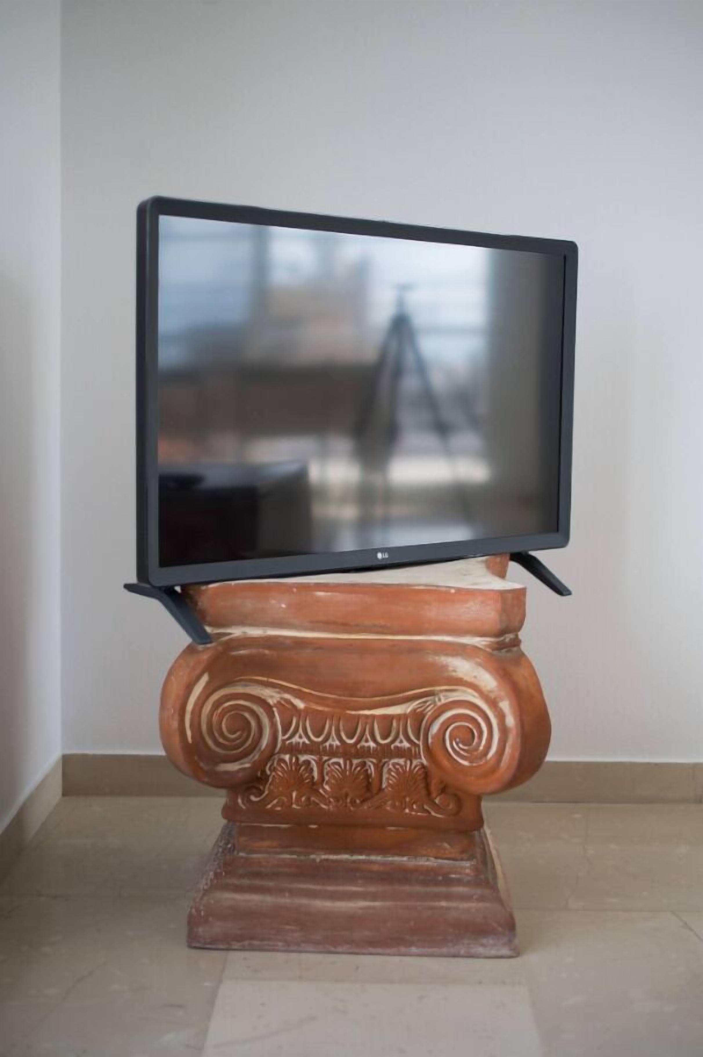 Uma televisão sobre um suporte decorativo.