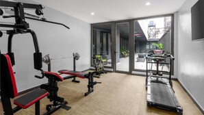 Uma academia com equipamentos de musculação, um banco e uma esteira.