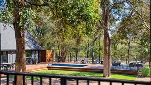 Uma área de piscina com deck, espreguiçadeiras e um edifício com telhado inclinado.
