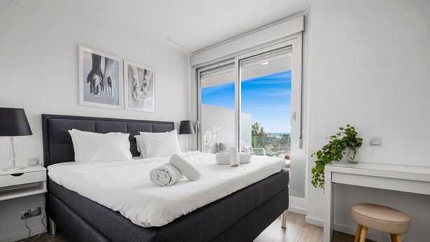 Quarto moderno com uma cama grande, uma escrivaninha e vista para o exterior.