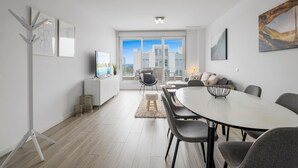 Uma sala de estar moderna com área de jantar, janelas amplas e obras de arte nas paredes.