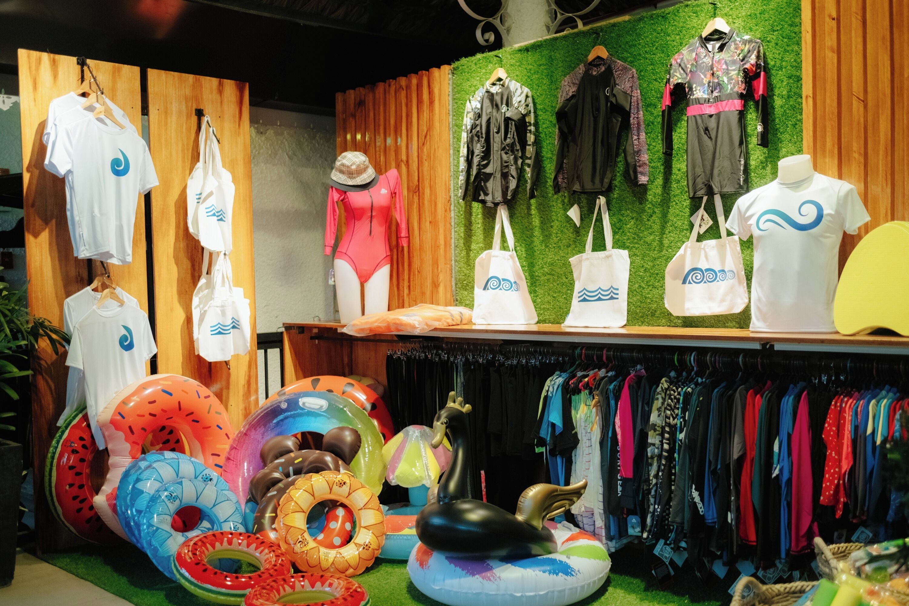 Uma loja de roupas com diversos trajes de banho, jaquetas e acessórios expostos em prateleiras e cabides.