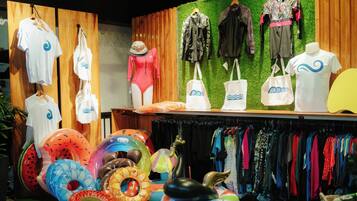 Uma loja de roupas com diversos trajes de banho, jaquetas e acessórios expostos em prateleiras e cabides.