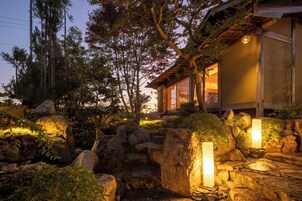 Um edifício tradicional japonês com fachada de madeira, caminho de pedra e lanternas iluminadas.