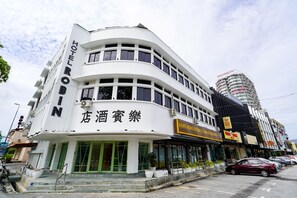 Um hotel com fachada curva, vários andares e uma placa em inglês e outro idioma.