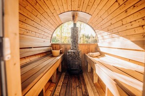 Uma sauna de madeira com bancos e um forno de pedra.