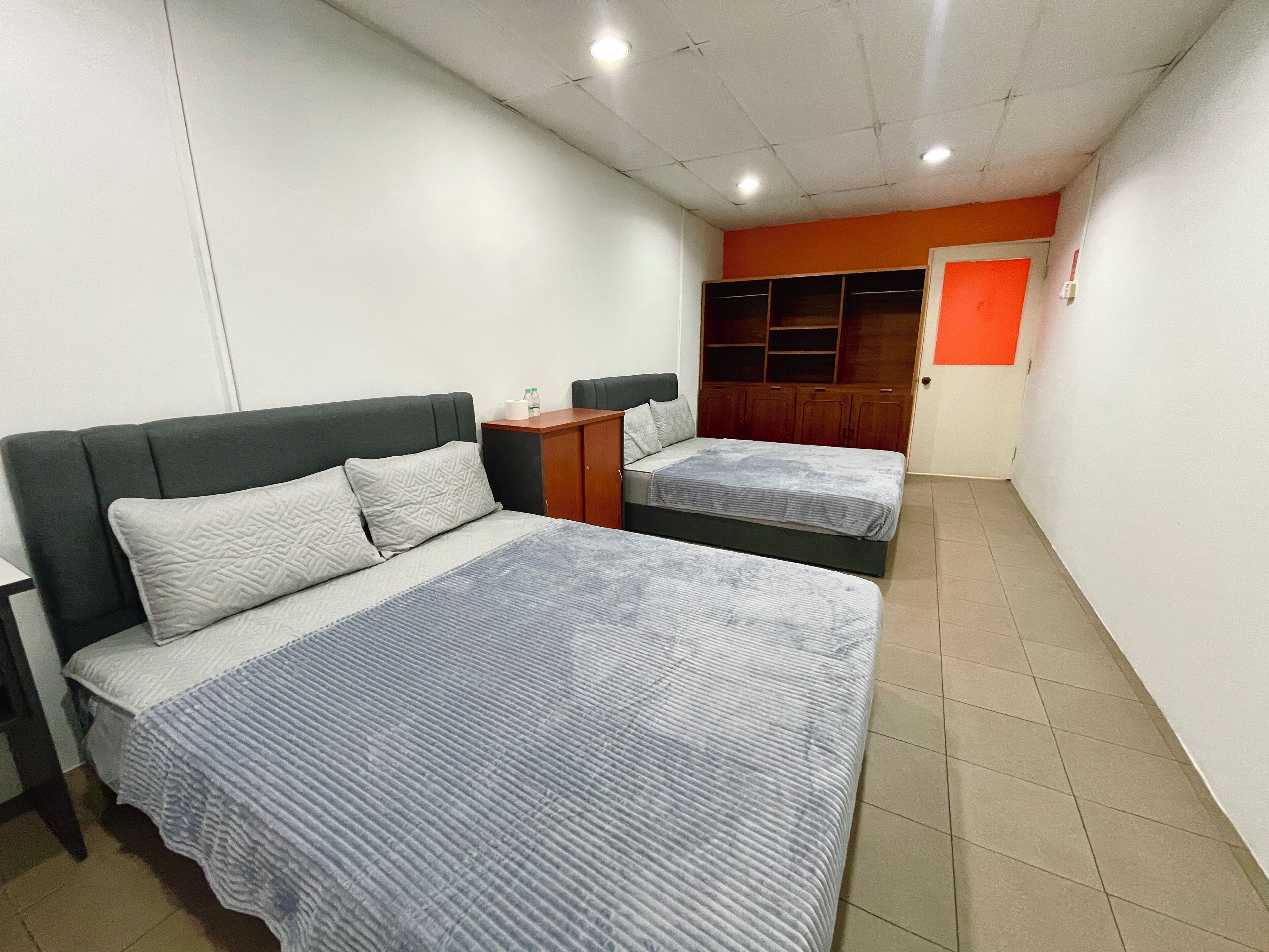 Quarto com duas camas, um guarda-roupa e uma mesinha.