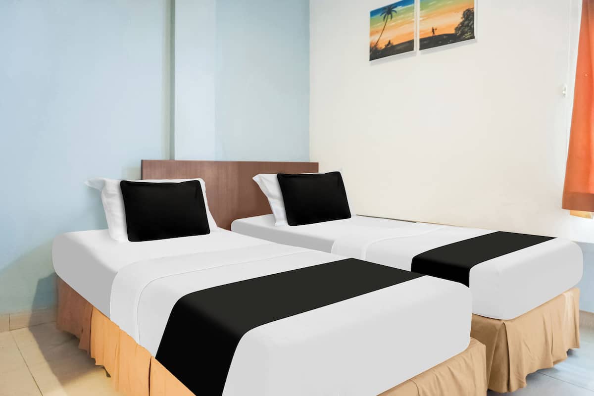Quarto de hotel com duas camas, cada uma com roupa de cama branca e cabeceiras pretas.