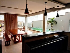 Uma cozinha moderna com ilha central, mesa de jantar de madeira e iluminação pendente.