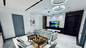 Uma sala de jantar moderna com piso de mármore, mesa com tampo de vidro e cadeiras estofadas cinzas.
