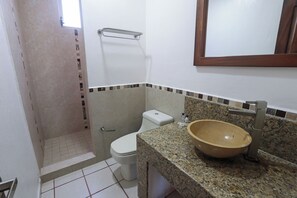 Casa de banho com sanita, lavatório e chuveiro.