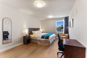 Quarto de hotel moderno com cama, escrivaninha, cadeira e um espelho grande.