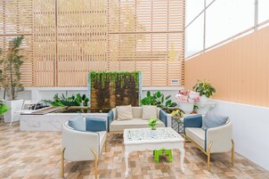 Uma área de estar moderna com sofás, uma mesa de centro e uma parede decorativa com plantas.