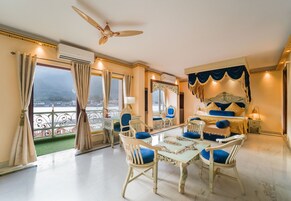 Um quarto espaçoso com varanda, cama com dossel e área de jantar com cadeiras e mesa.