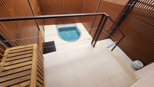 Uma área de piscina com piso ladrilhado, deck de madeira e guarda-corpo de metal.